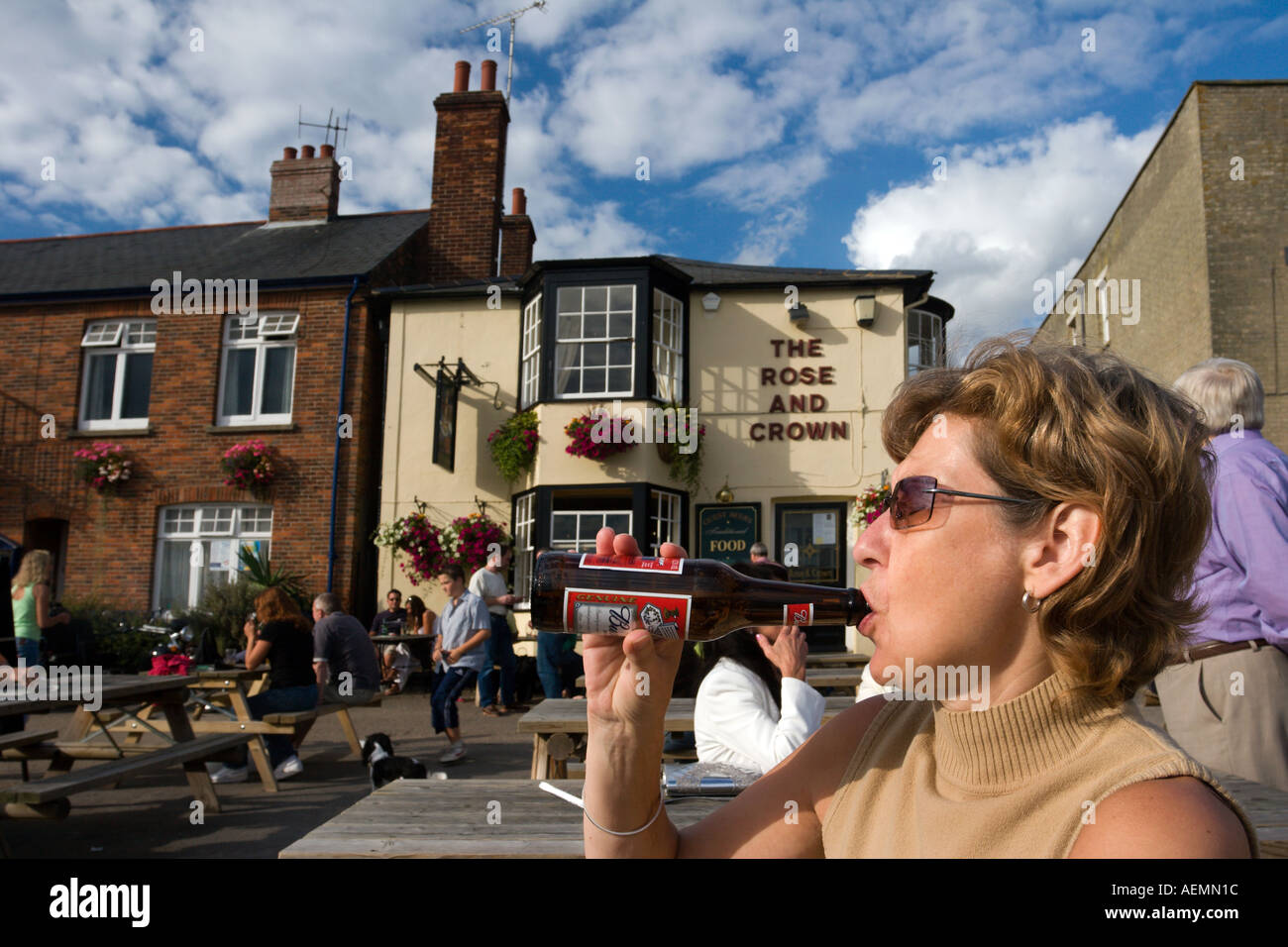 A middle aged woman drinks from a bottle of beer at The Rose and Crown ...