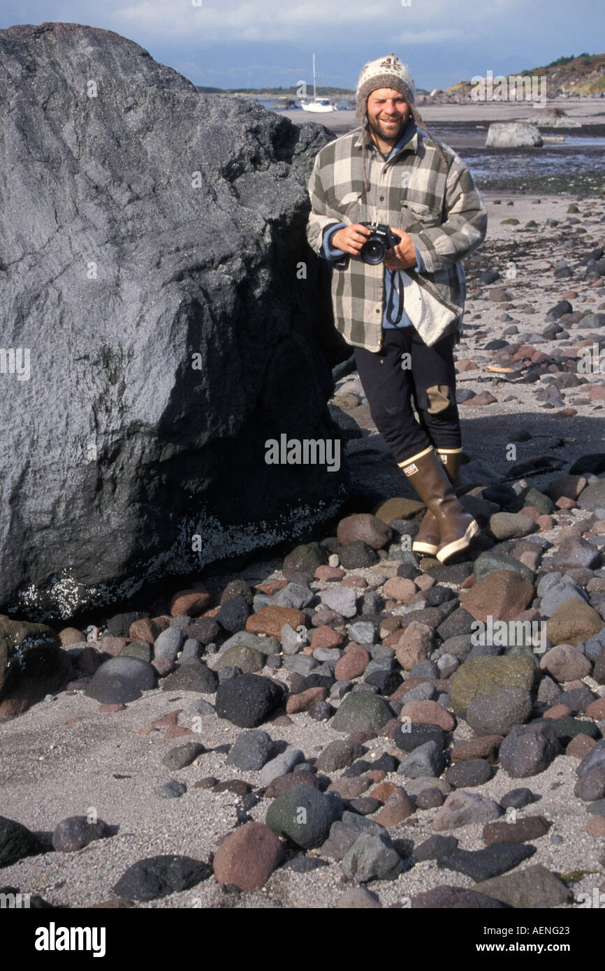 photographer Steven Kazlowski stands next to a boulder on a beach he ...