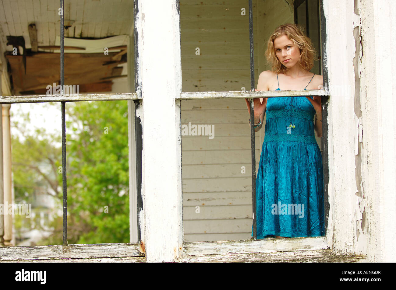 A beautiful young woman gazes out from behind an old window frame Stock ...