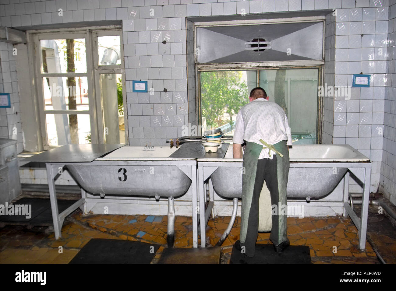 Prisoner leaning over large cleaning washing sinks in prison kitchen ...