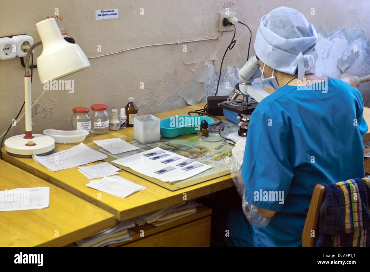 Female nurse, back to camera, examines sample through microscope Stock ...