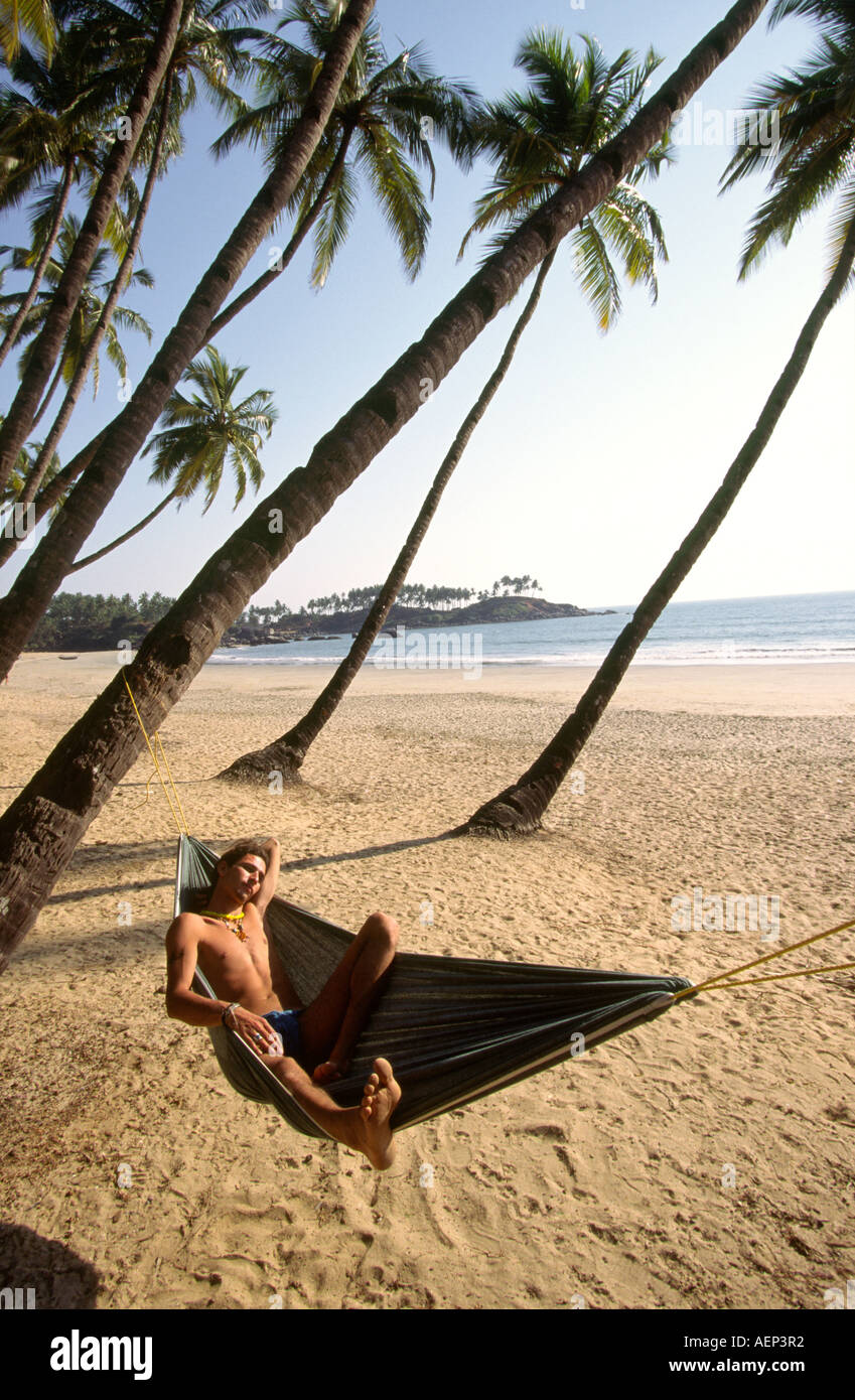 India Goa Palolem man in hammock beside palm fringed beach Stock Photo ...