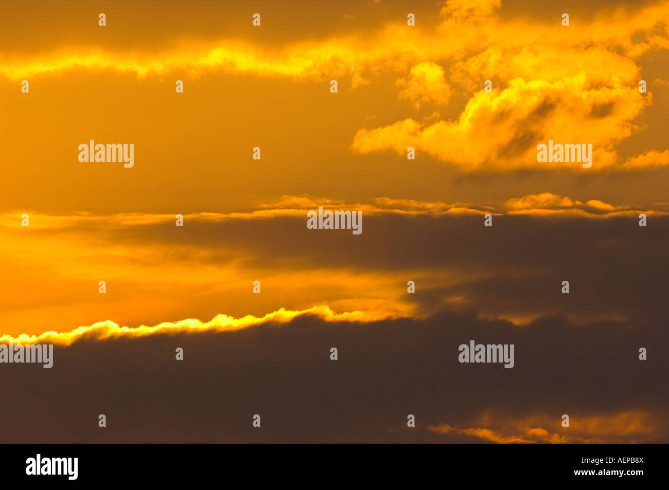 The sun dropping down from under cloud cover giving a red warm glow to ...