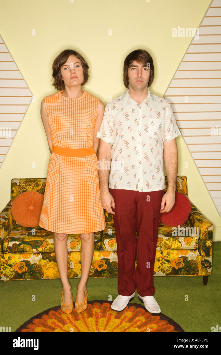 Caucasian mid adult couple wearing retro clothes standing stiffly in ...