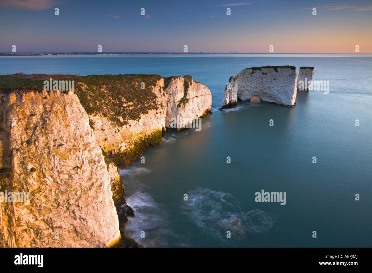 Sunrise colours the white chalk cliffs of Old Harry Rocks golden ...