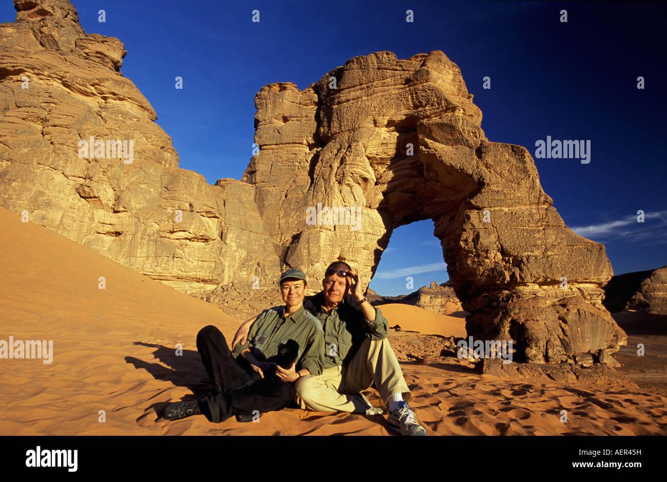 Libya Akakus Cliffs in Sahara Desert, Tourists resting at natural arch ...