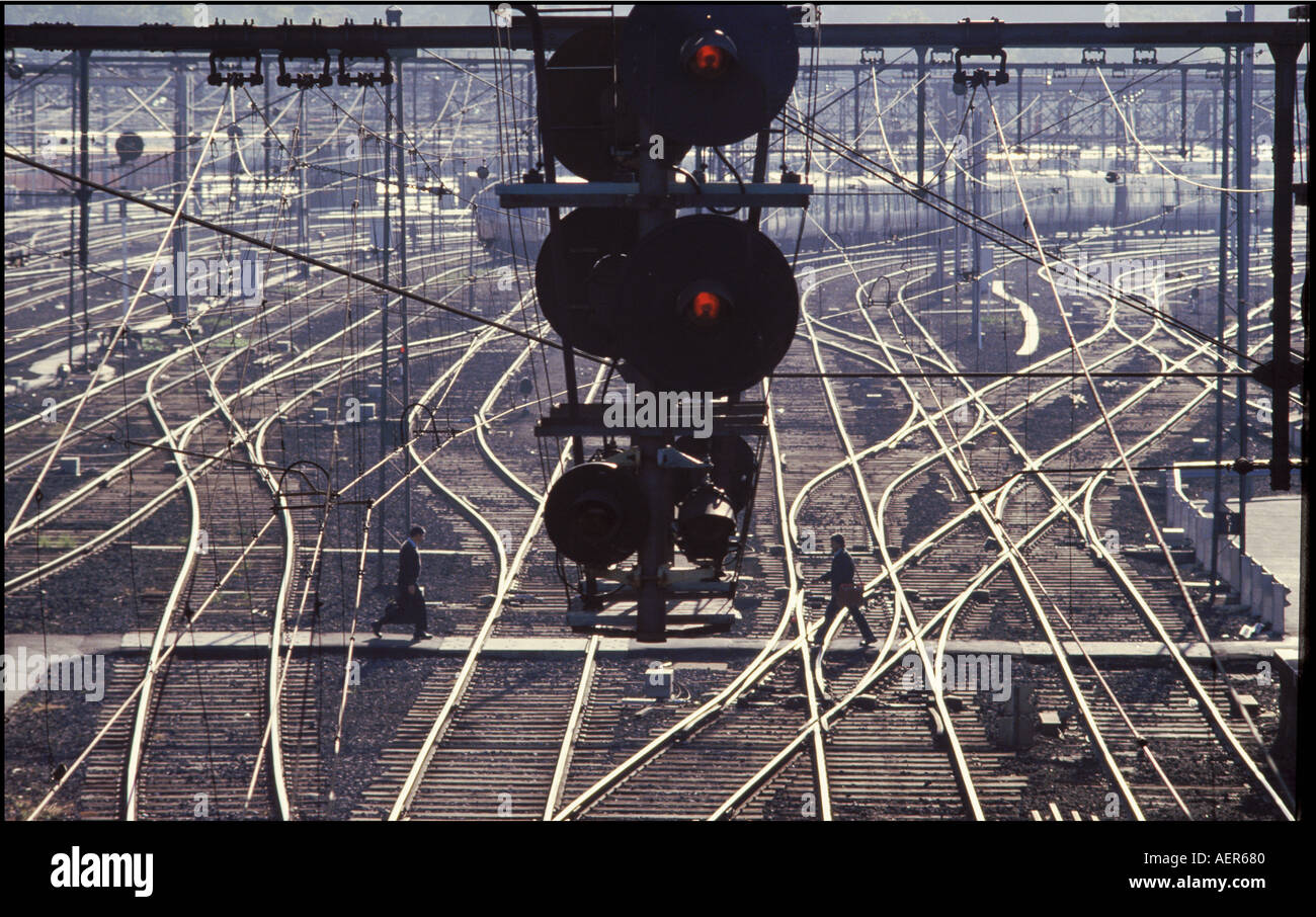 Two men crossing the railway tracks at a junction railway signals show ...