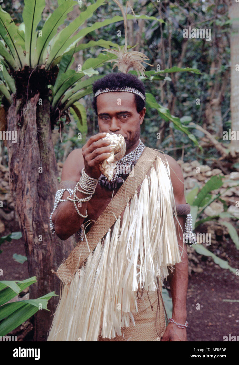 Man blowing into shell horn indicating visitors are approaching Ekasup ...