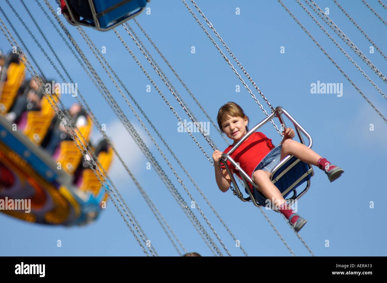 Small girl flying in the chain chair of merry go round Stock Photo - Alamy