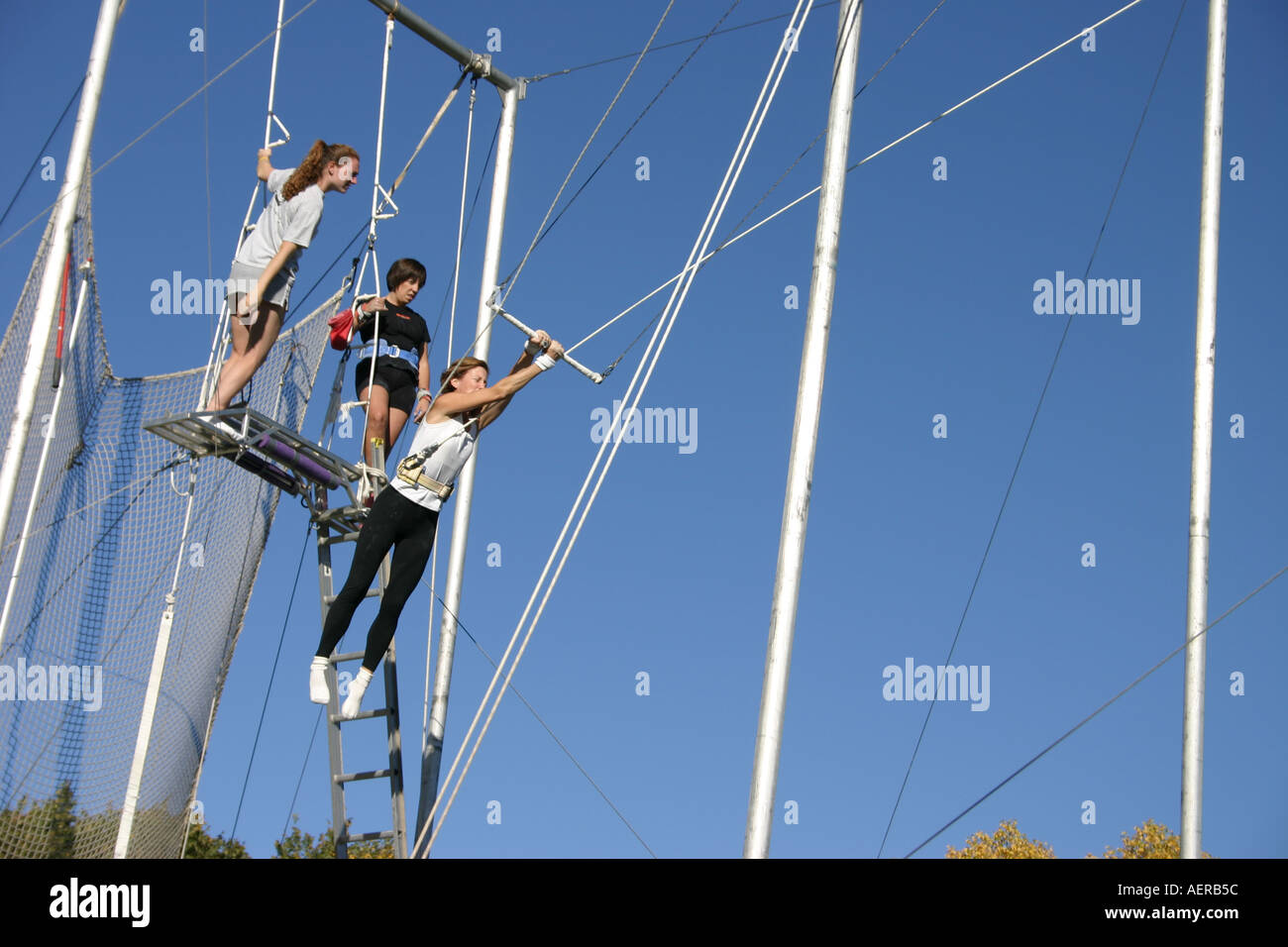Woman trapeze artist jumps off platform while two women look on Stock ...
