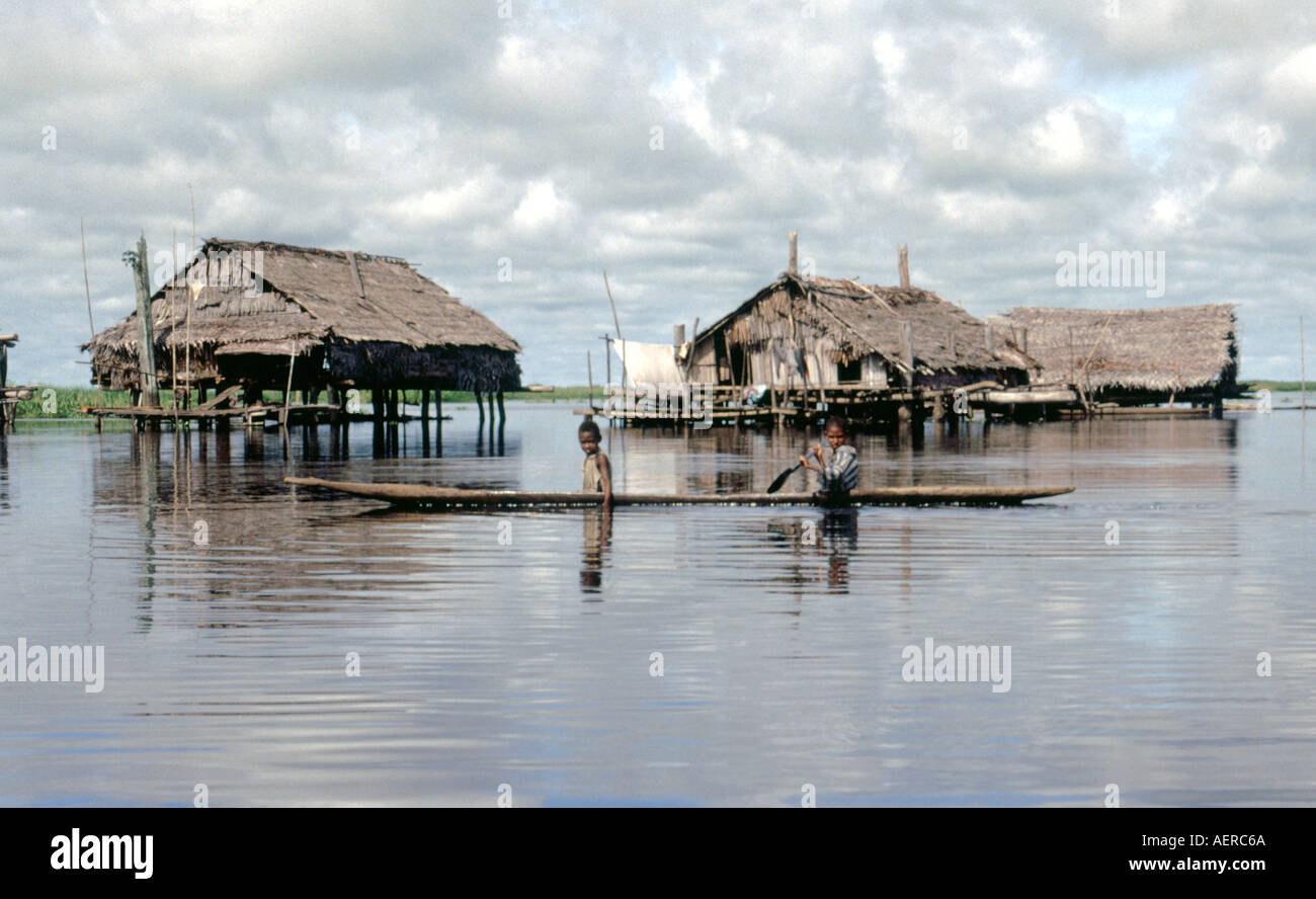 Children in a canoe pass by houses on the flooded Sepik River Papua New ...