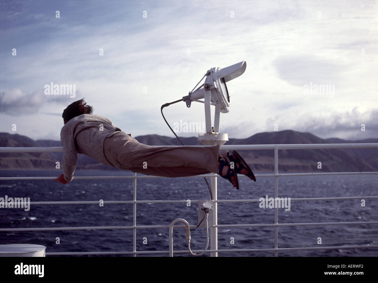 Man holding on to rail being blown by high winds on ship deck Stock ...