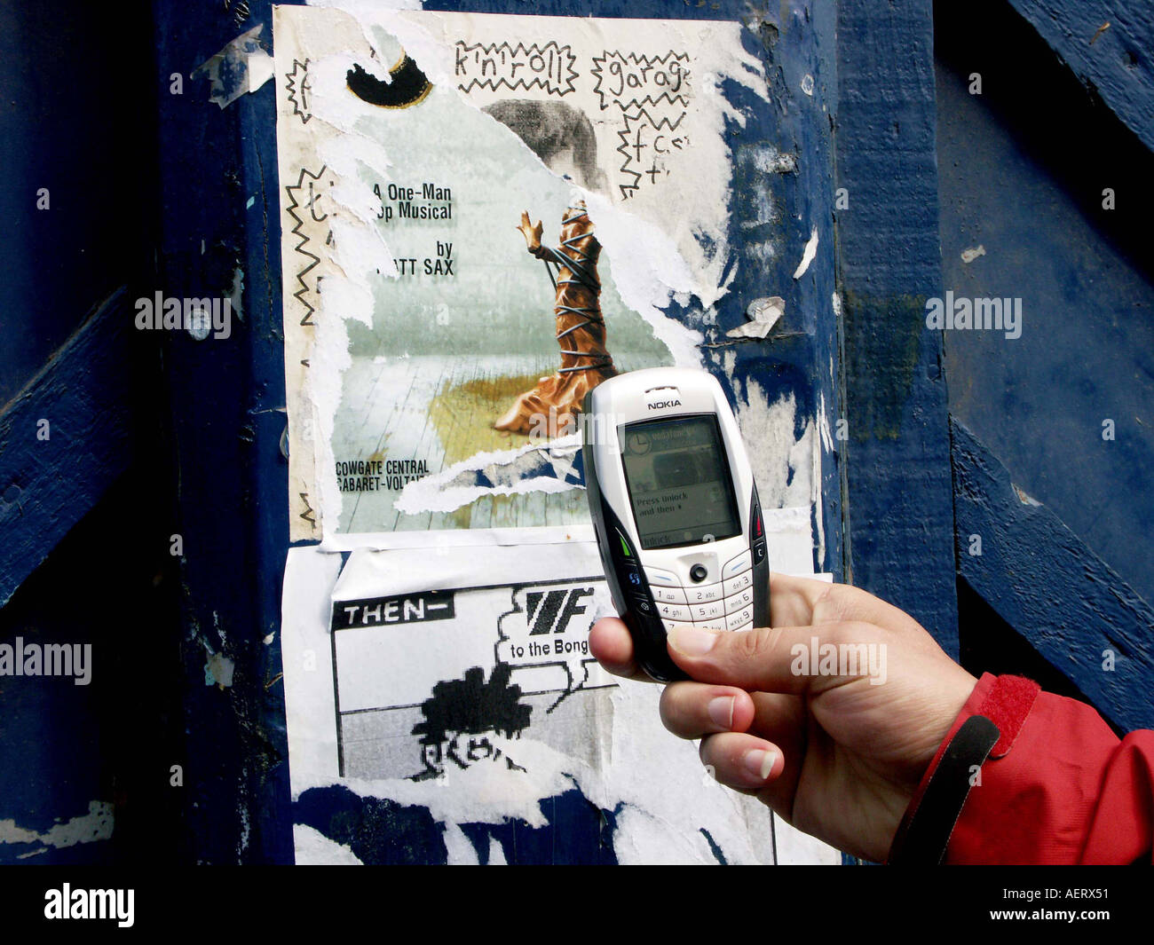 a hand taking a picture with a nokia mobile phone of poster graffiti in ...