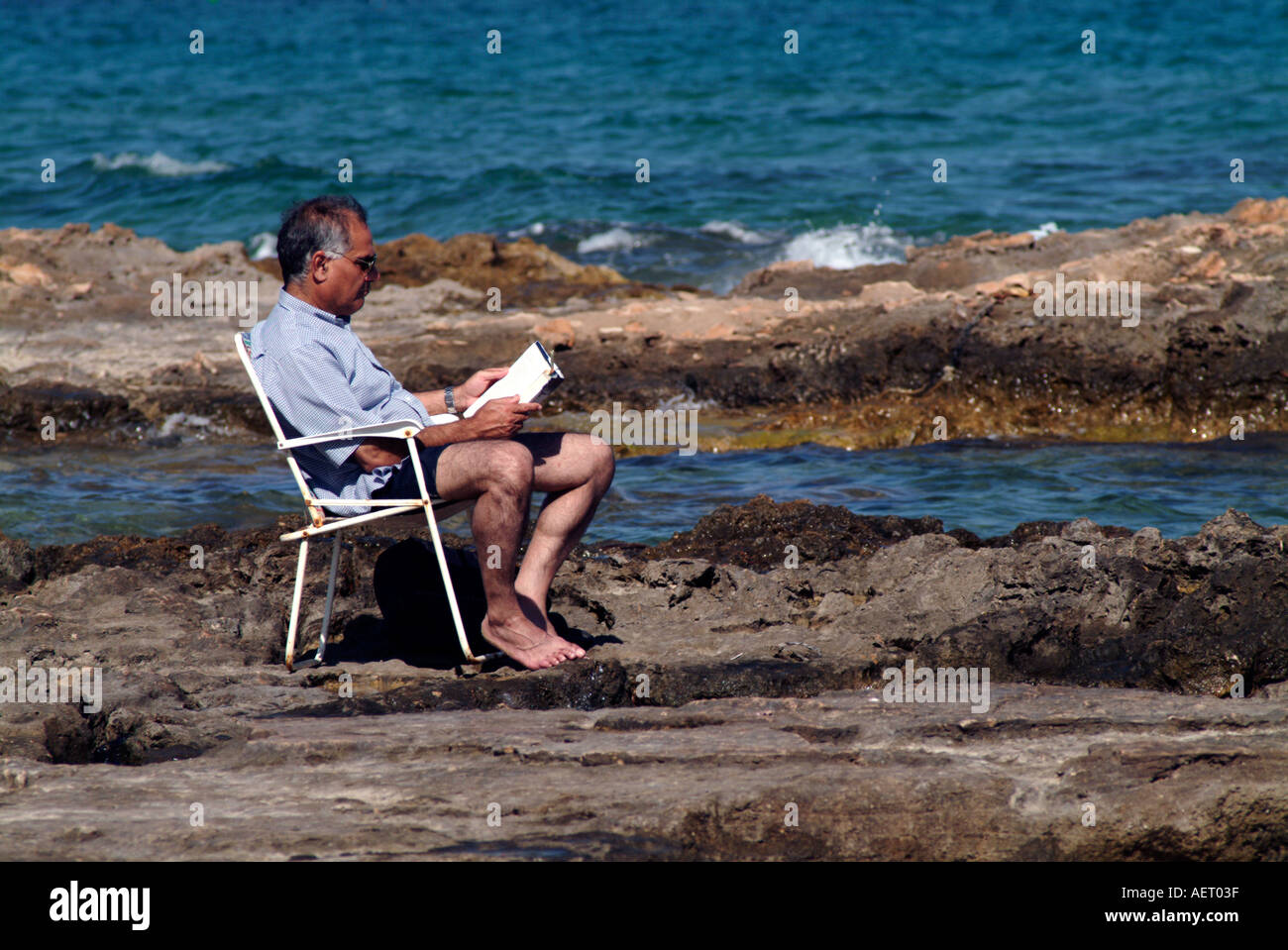 man sitting in Sun beside sea Spain Stock Photo - Alamy