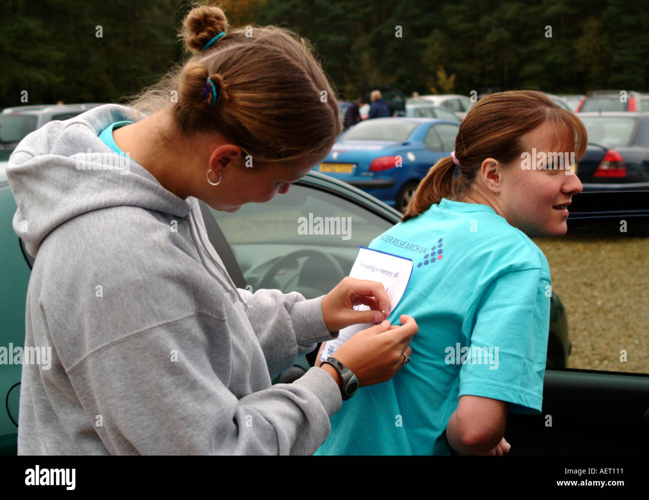 young women pins number on womans back Stock Photo - Alamy