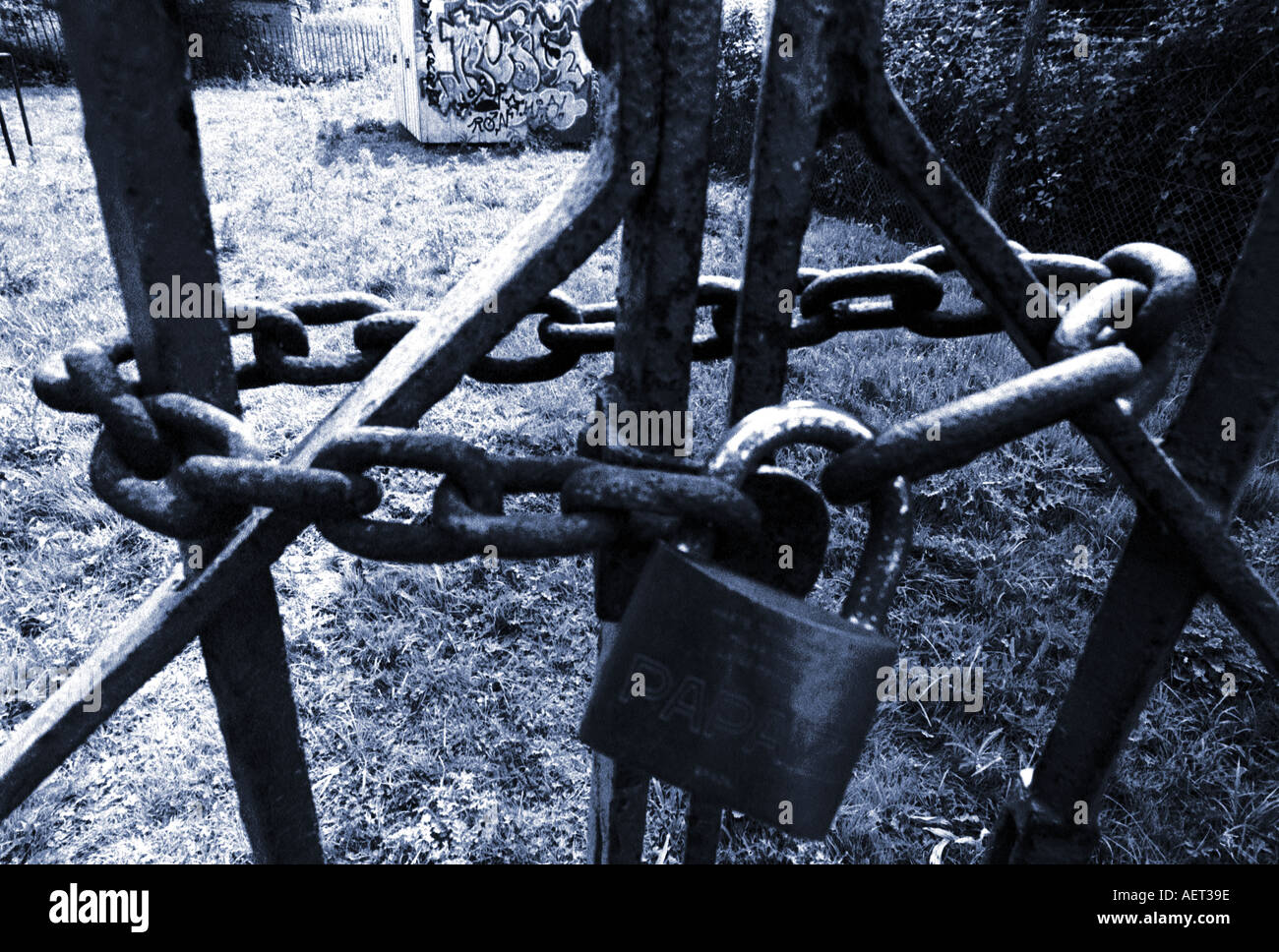 gate lock with building covered in graffiti in black and white, with ...