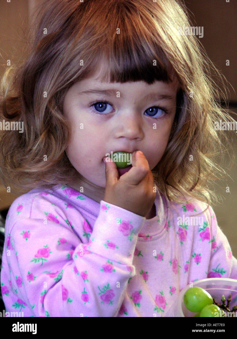 Small girl eating a grape Stock Photo - Alamy