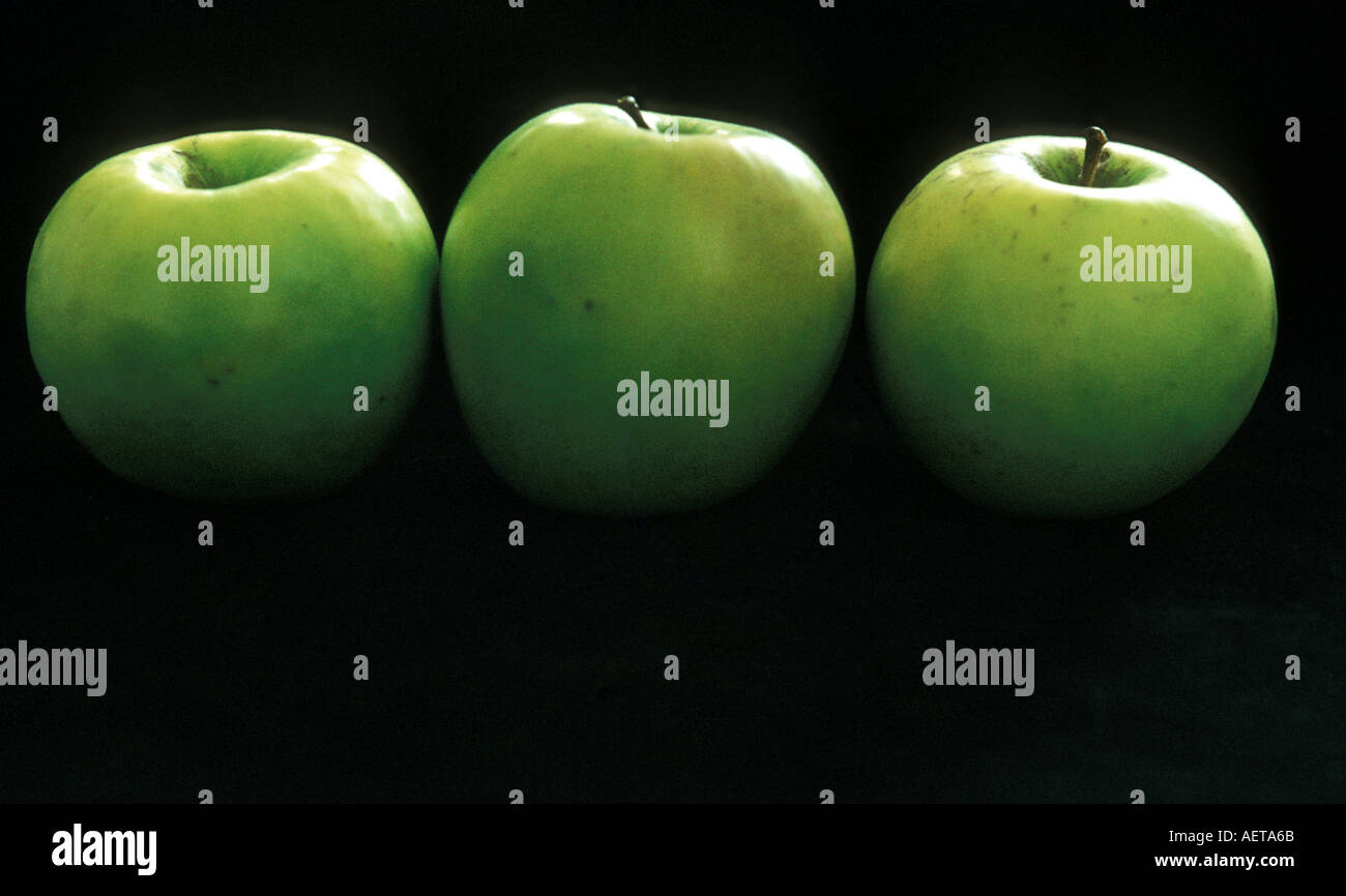 Three green apples in a row against a black background Stock Photo - Alamy