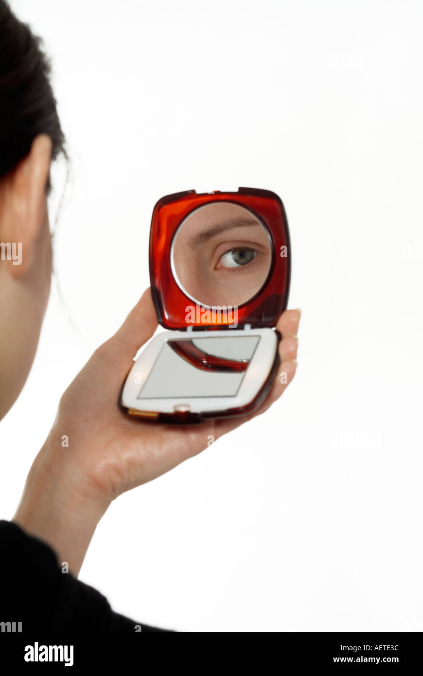 Woman looking into a compact mirror Stock Photo - Alamy