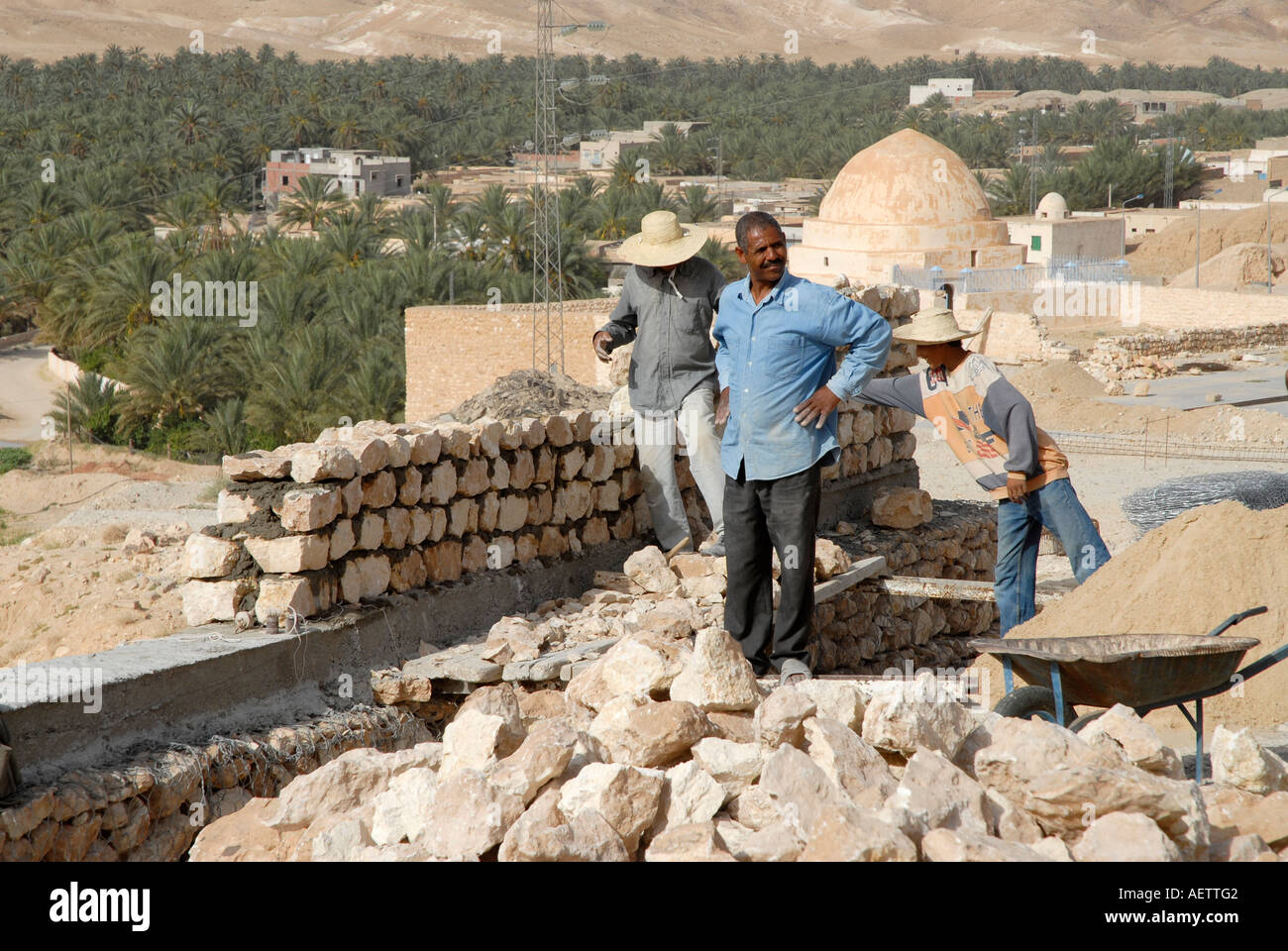 workman building a wall of a new developement overlooking Old Tamerza ...