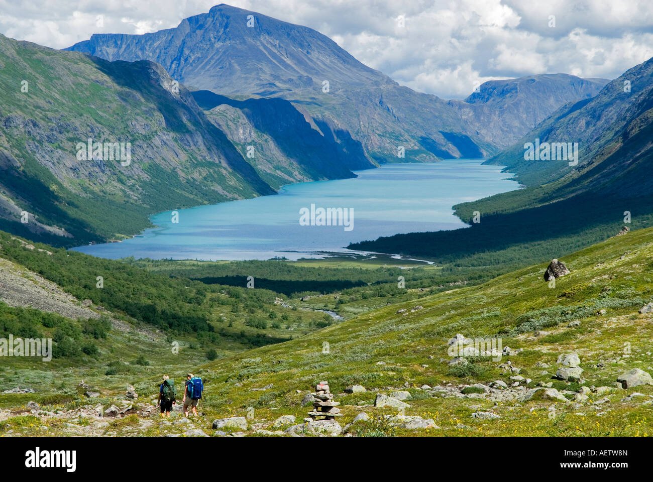 two hikers hike towards lake Gjende in mountains of Jotunheimen ...