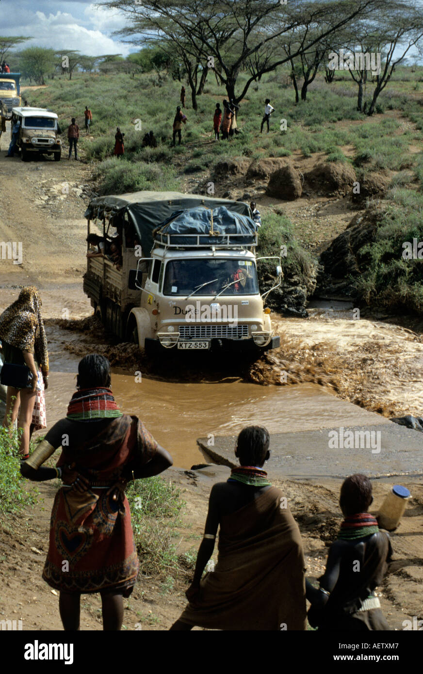 Overland lorry crosses a ford in northern Kenya, watched by women from ...