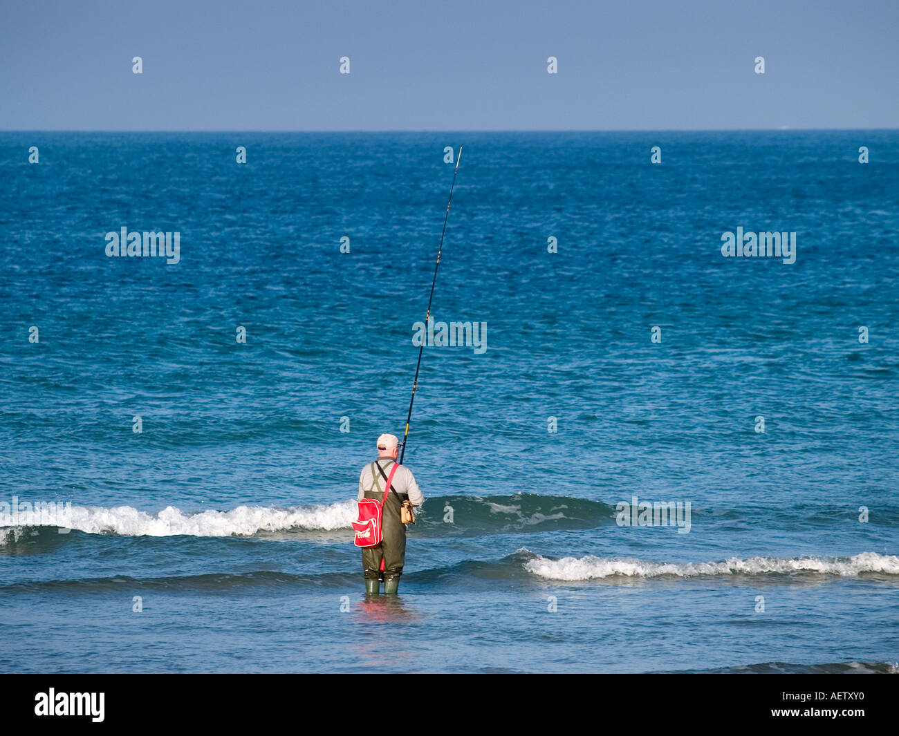 Sea angler fishing from the beach Stock Photo - Alamy