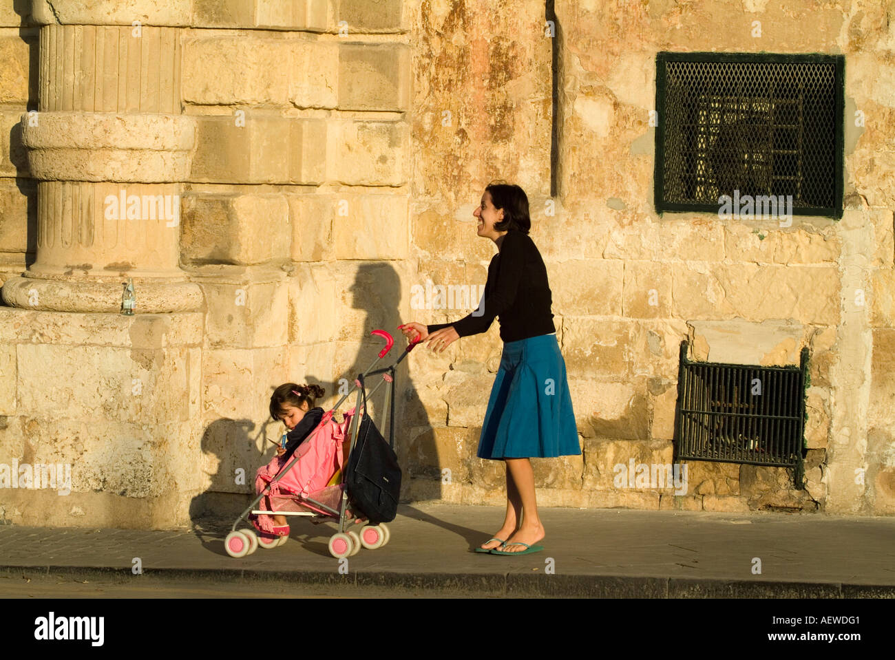 Mother pushers young toddler along in a push-chair, on holiday in Malta ...