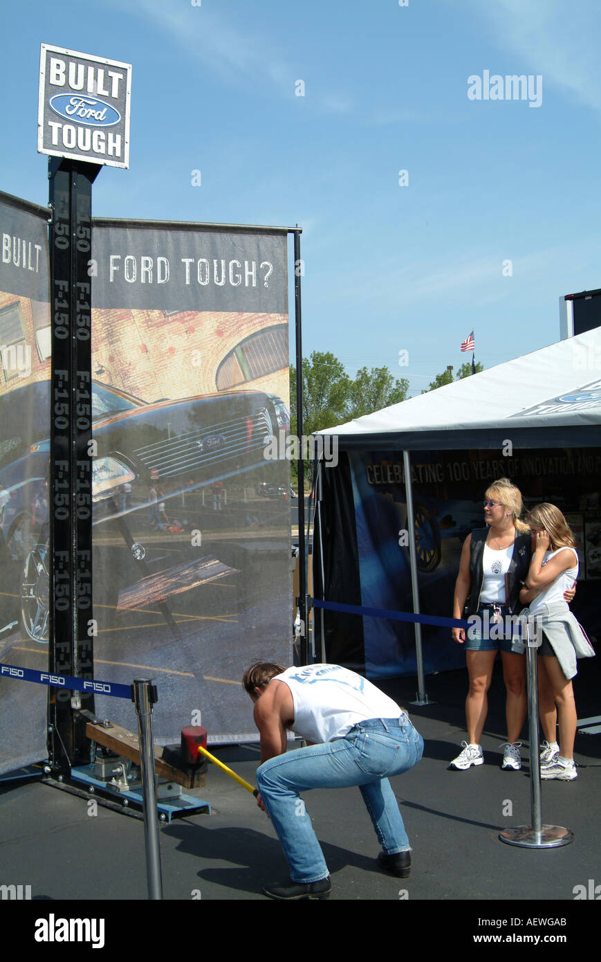 A man trying to ring the bell by hitting rubber stump with hammer while ...