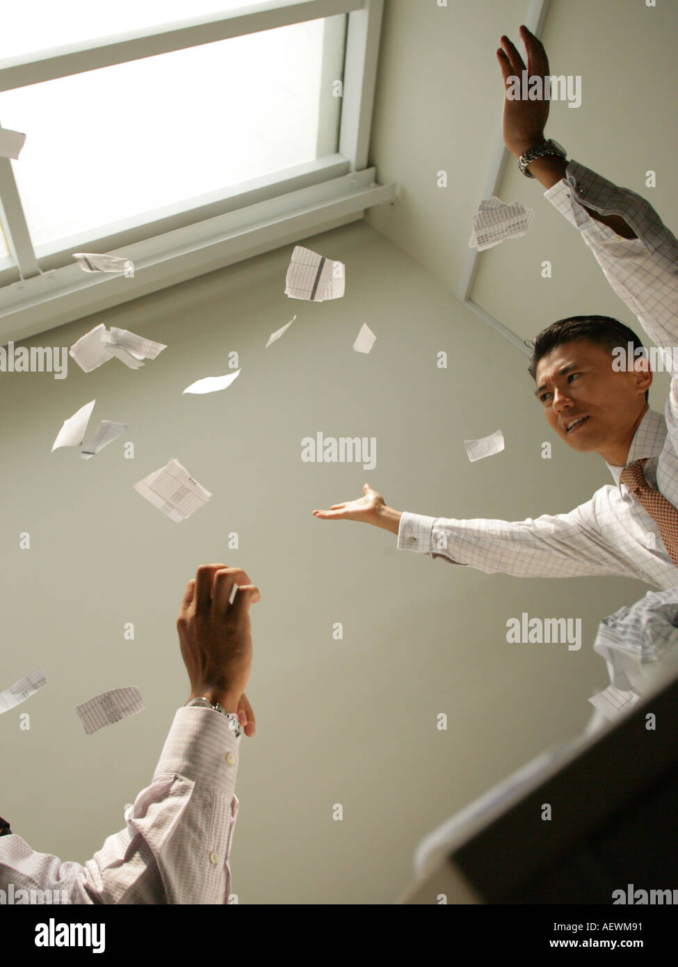 Low angle view of two businessmen throwing pieces of paper into the air ...