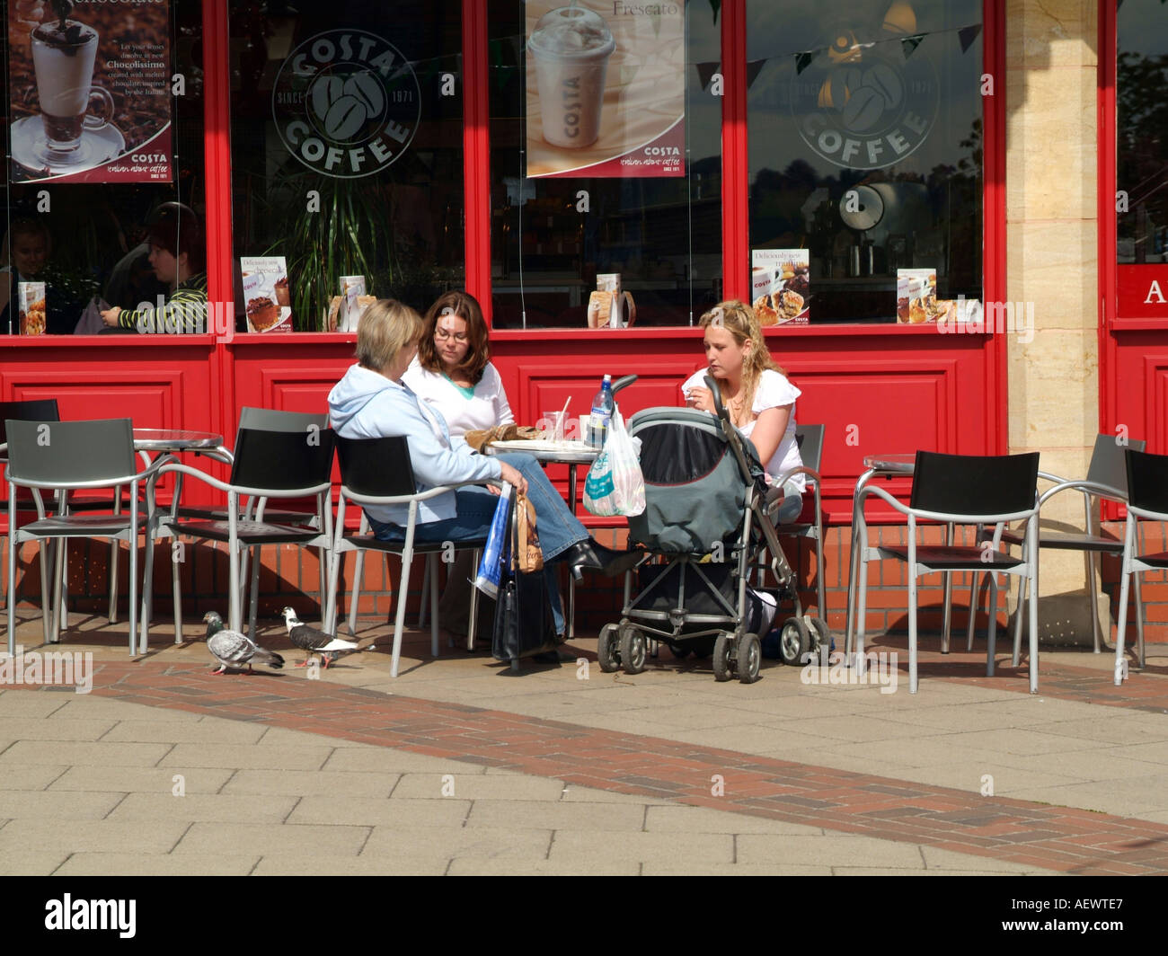 A group of young women sitting outside a cafe having a chat and a ...