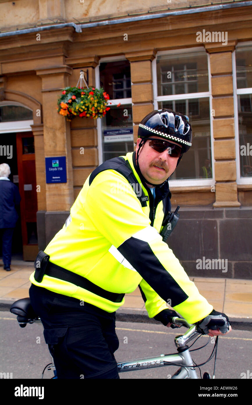 English Policeman on a bicycle wearing a sfaety helmet and sunglasses ...