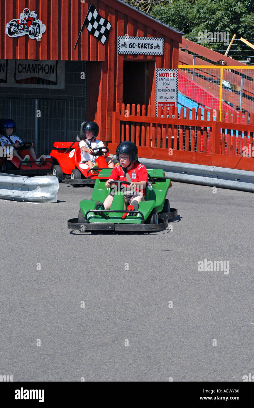 Children having fun driving go-karts around a track at an amusement ...