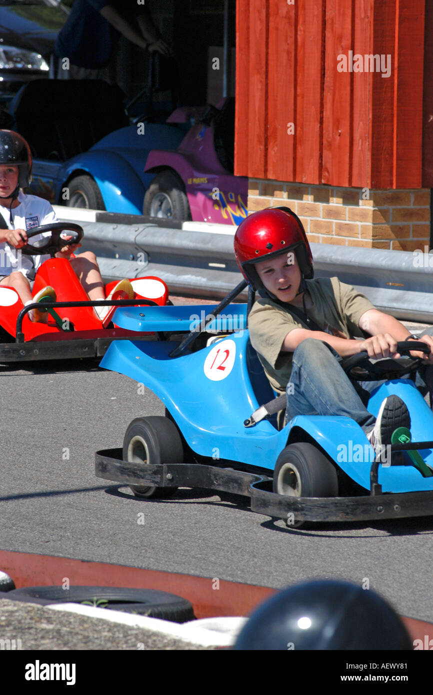 Children having fun driving go-karts around a track at an amusement ...