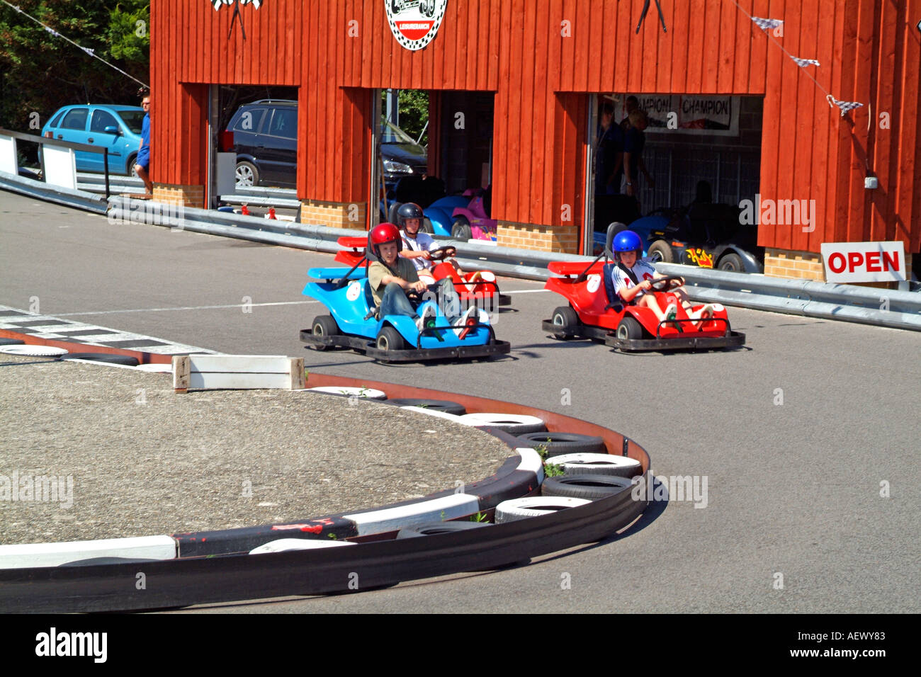 Children having fun driving go-karts around a track at an amusement ...