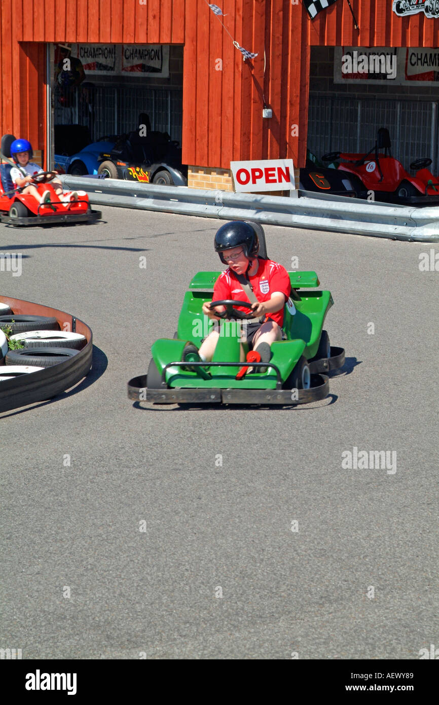 Children having fun driving go-karts around a track at an amusement ...