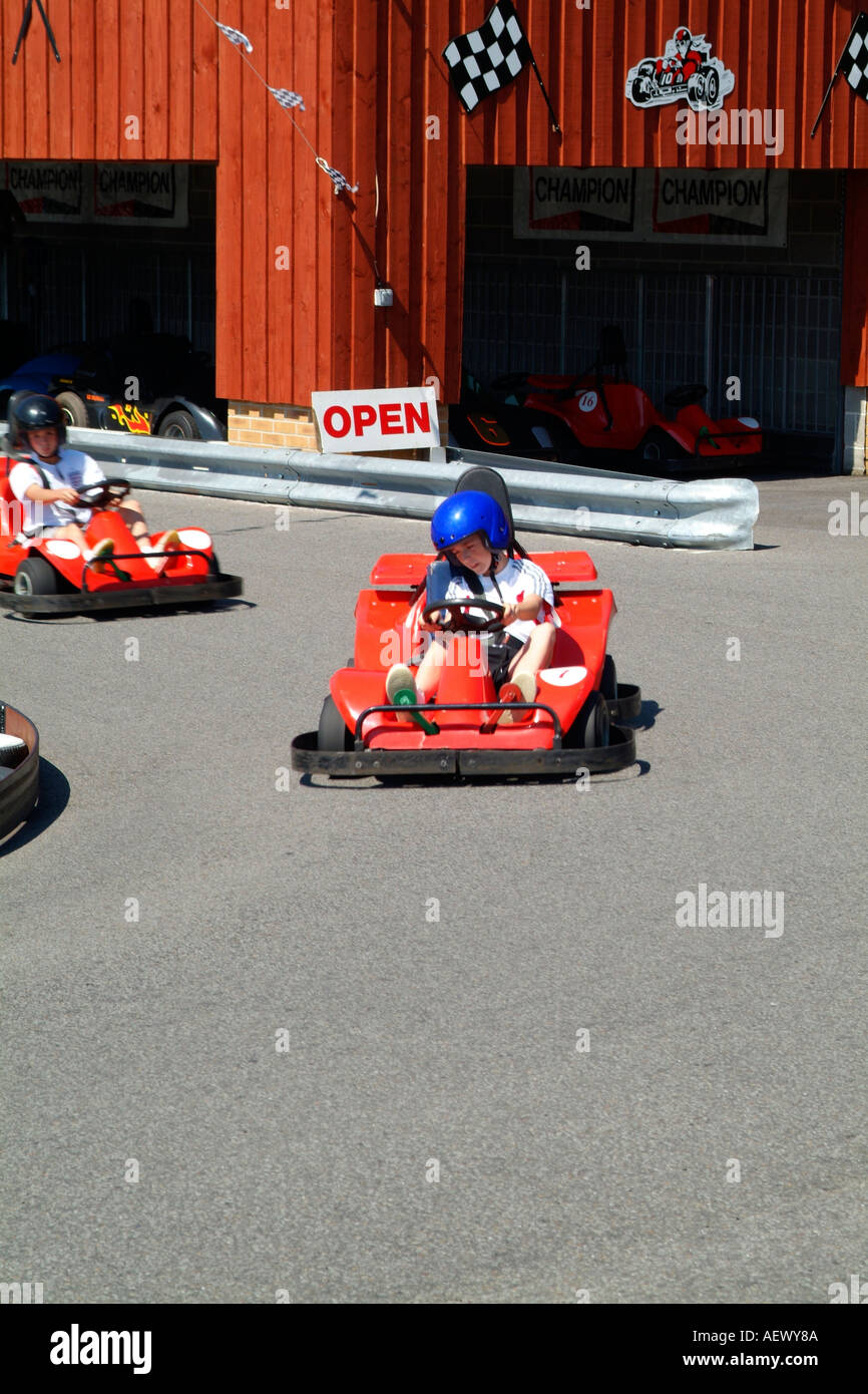Children having fun driving go-karts around a track at an amusement ...