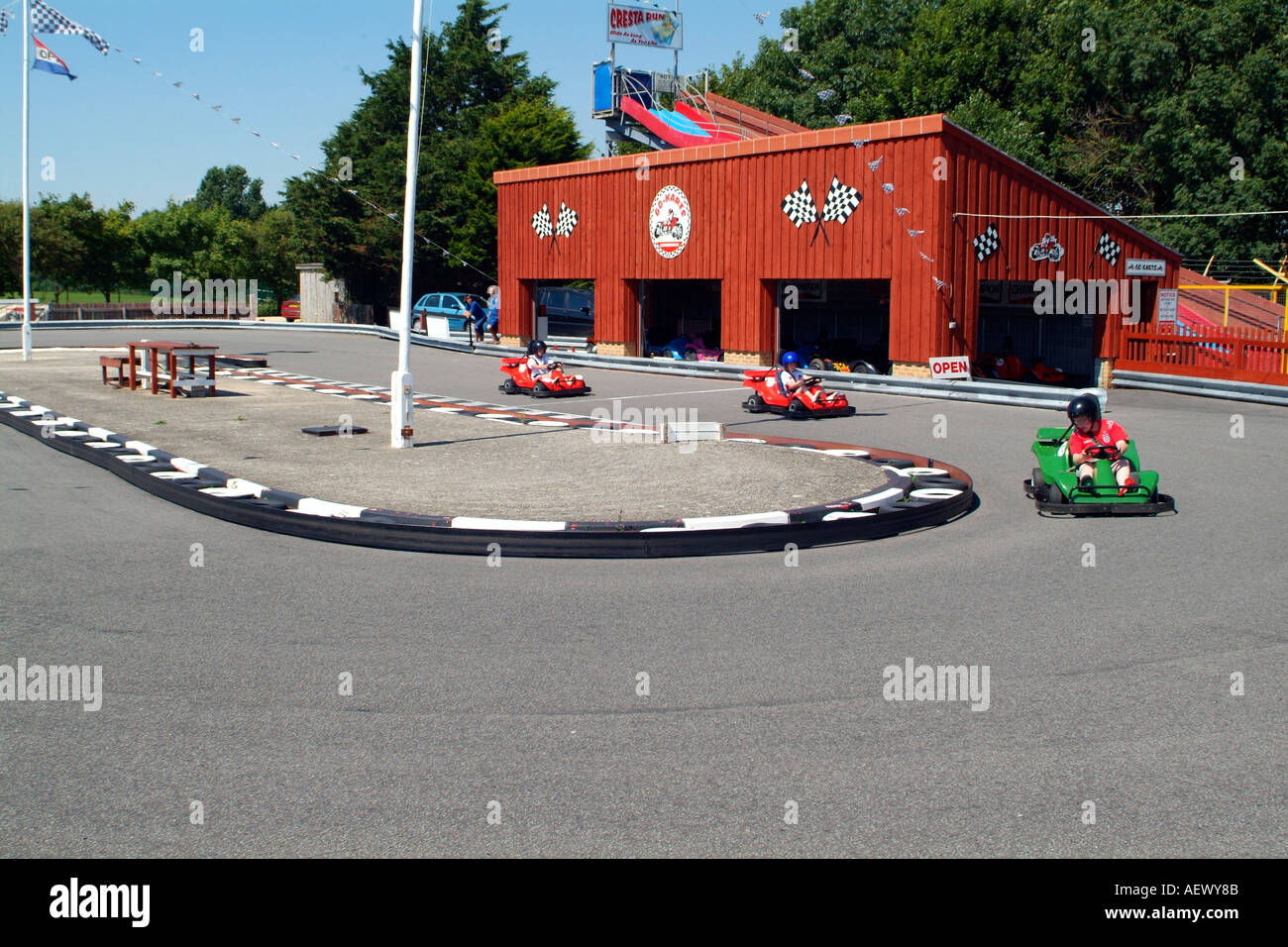 Children having fun driving go-karts around a track at an amusement ...
