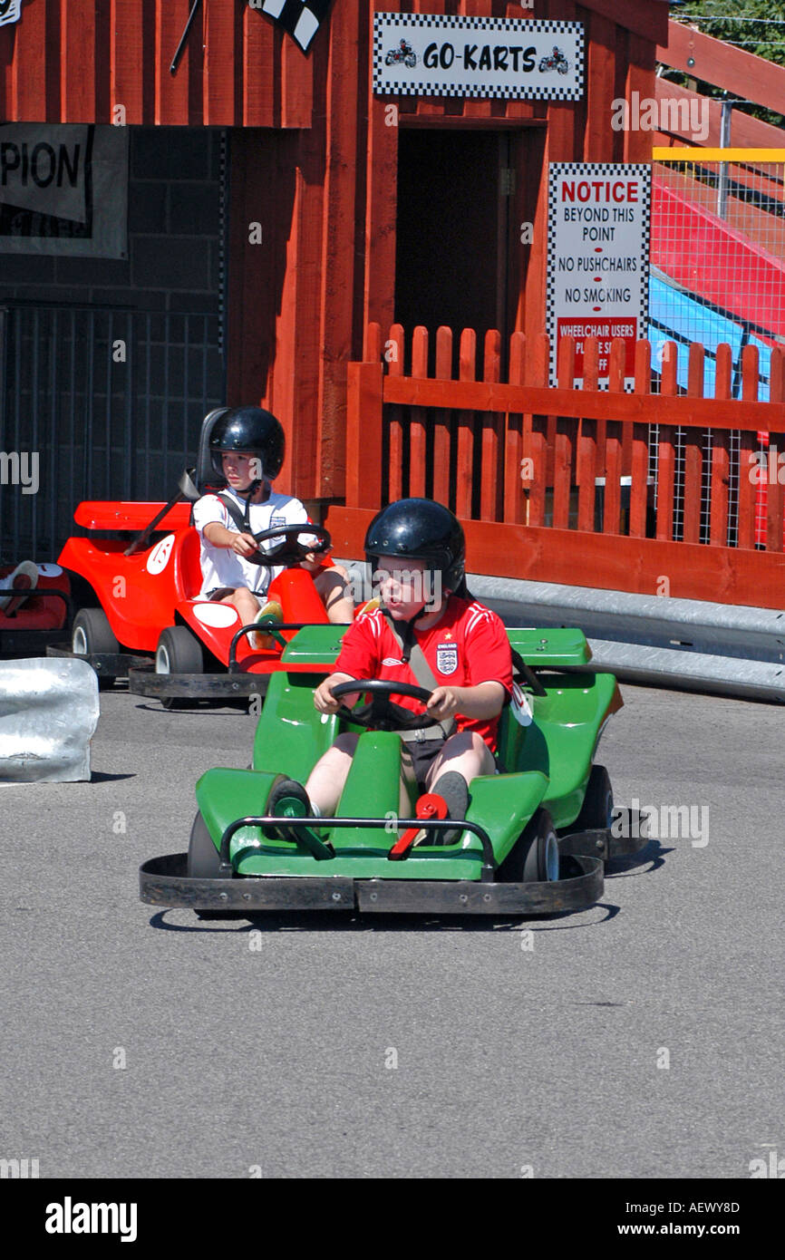 Children having fun driving go-karts around a track at an amusement ...