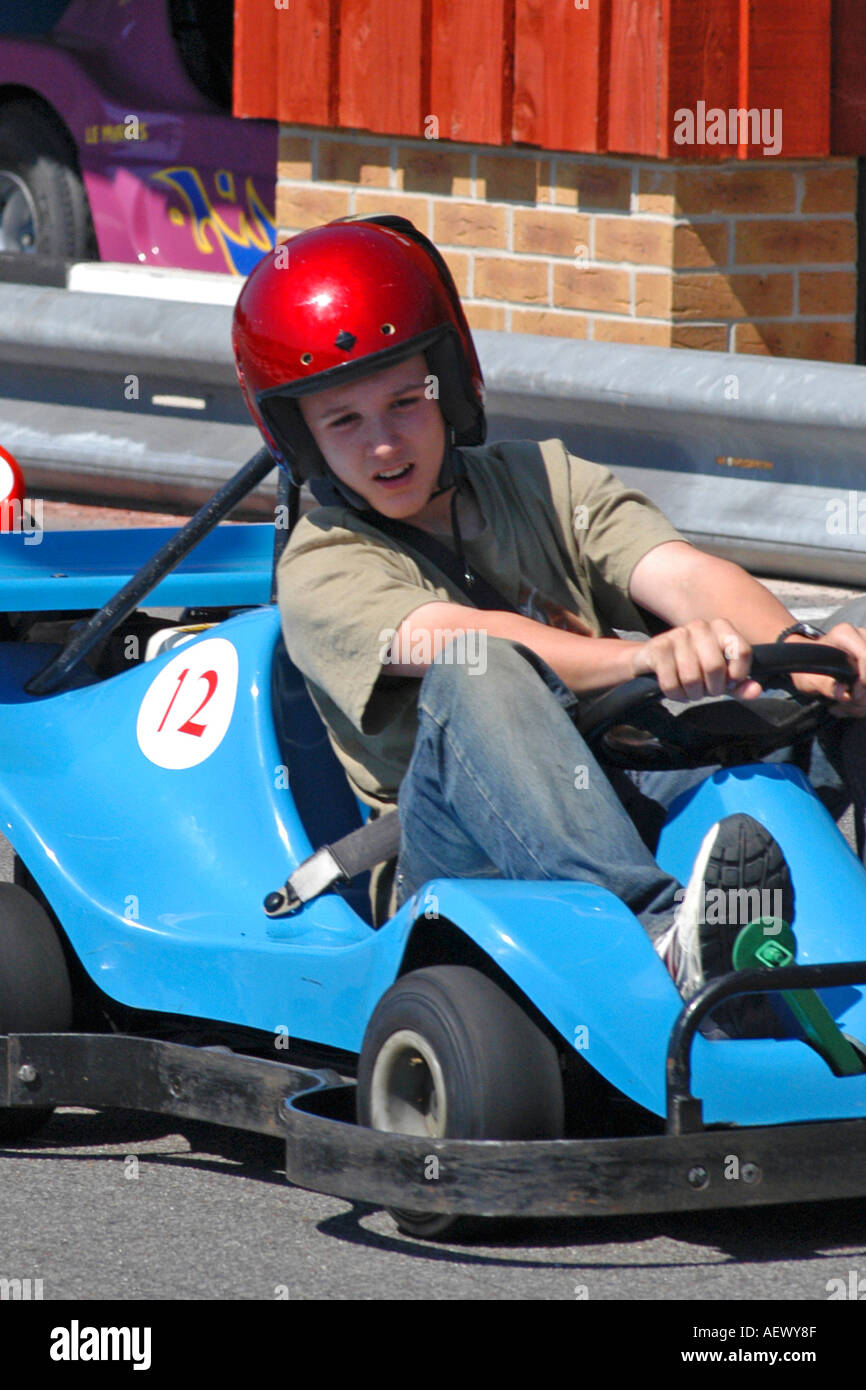 Children having fun driving go-karts around a track at an amusement ...