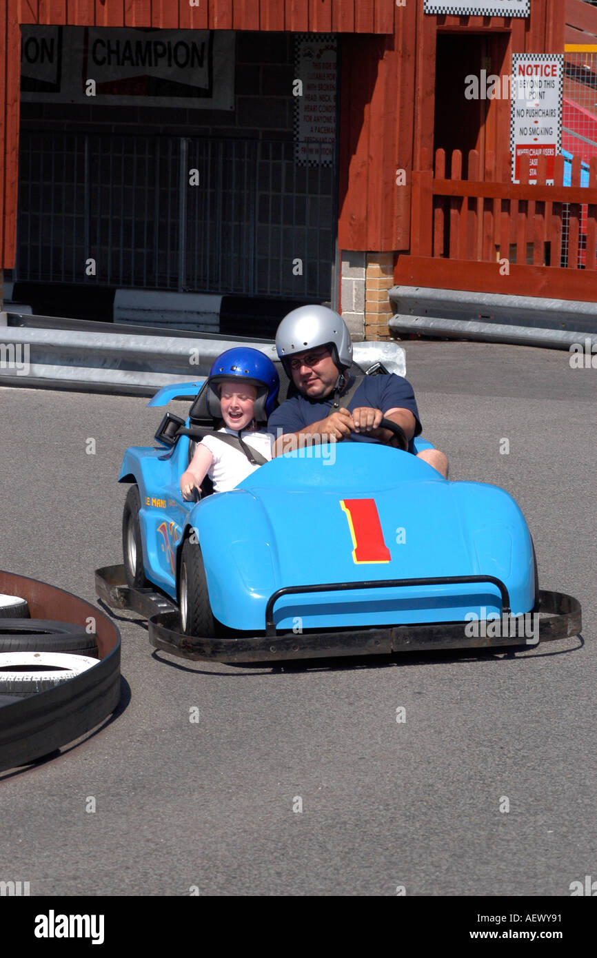 Children having fun driving go-karts around a track at an amusement ...