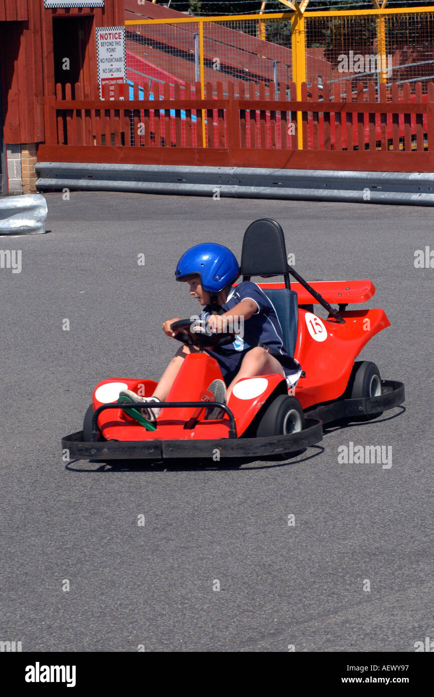 Children having fun driving go-karts around a track at an amusement ...