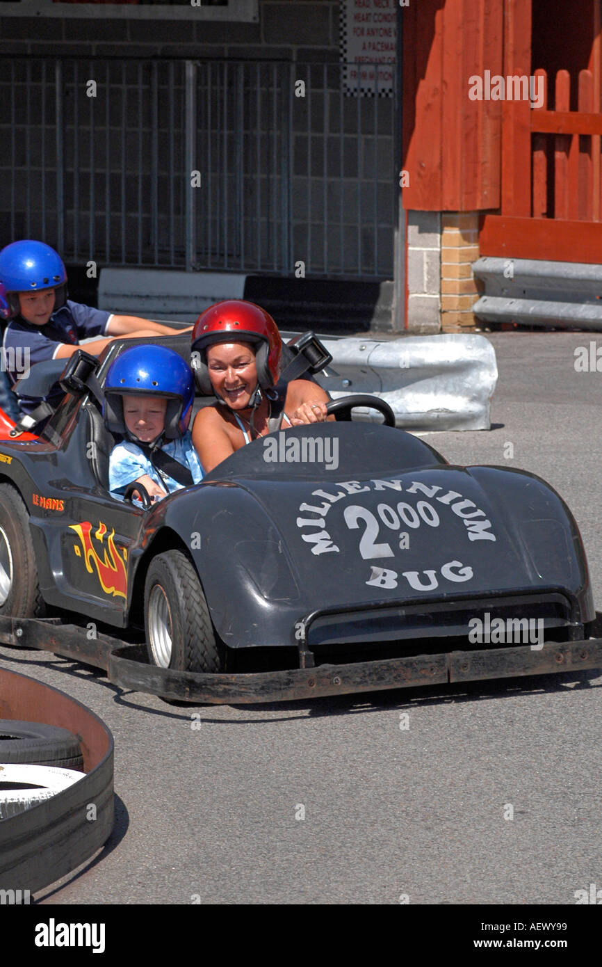 Children having fun driving go-karts around a track at an amusement ...