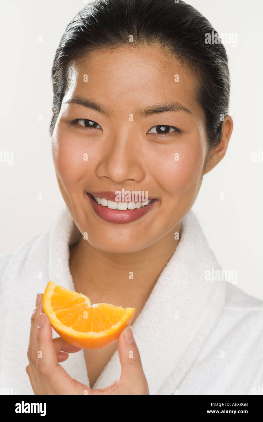 Portrait of a woman eating orange slice Stock Photo - Alamy