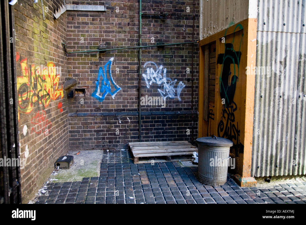 Urban scene. Alley way, dustbin, pallet and graffiti Brighton uk Stock ...