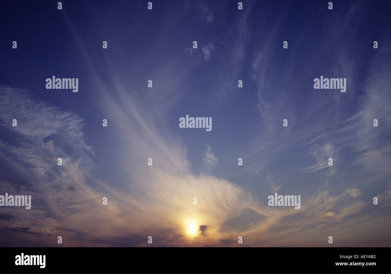 Yellow sun in cloud streaked sky Stock Photo - Alamy