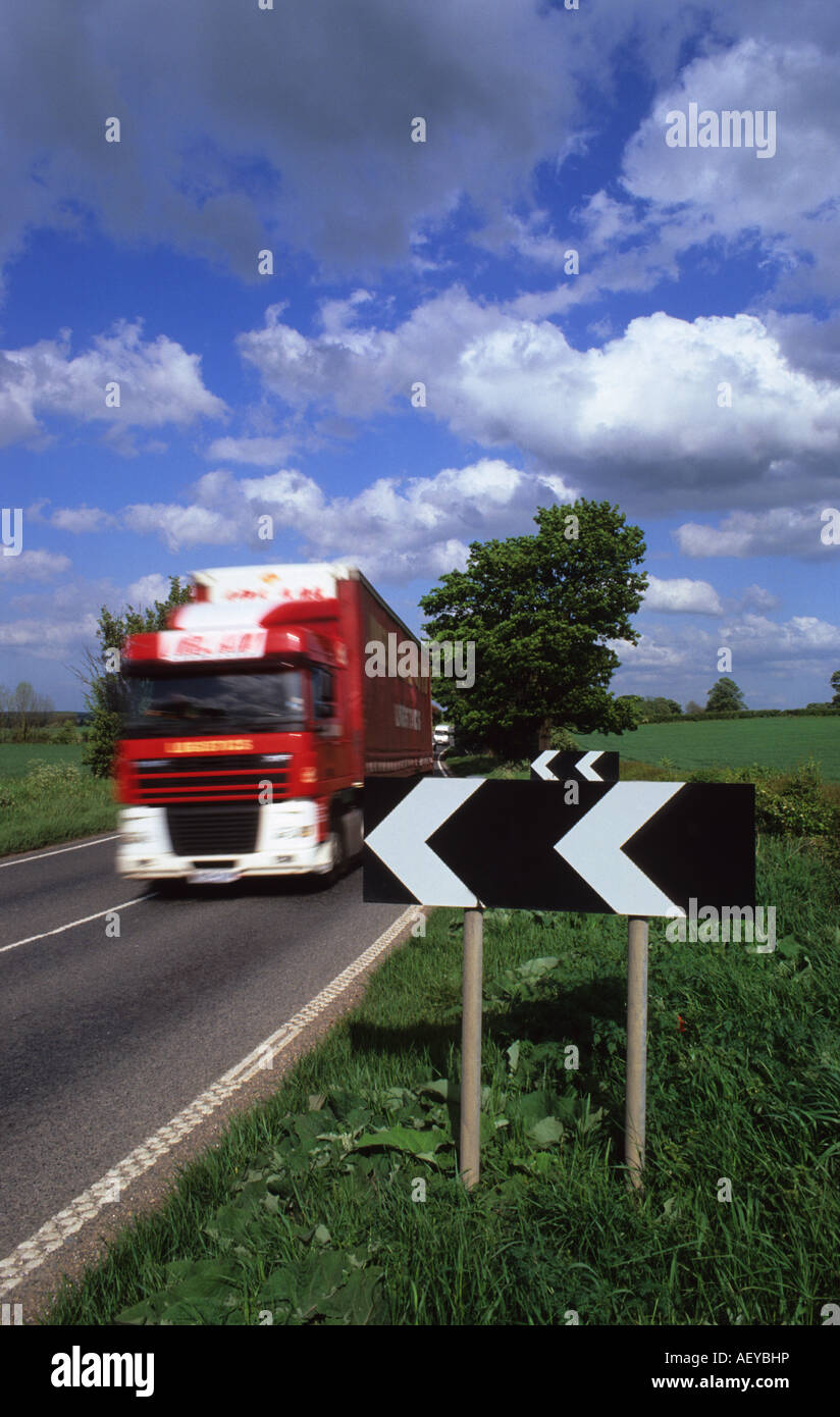 lorry passing black and white chevron signs warning of bend in the road ...