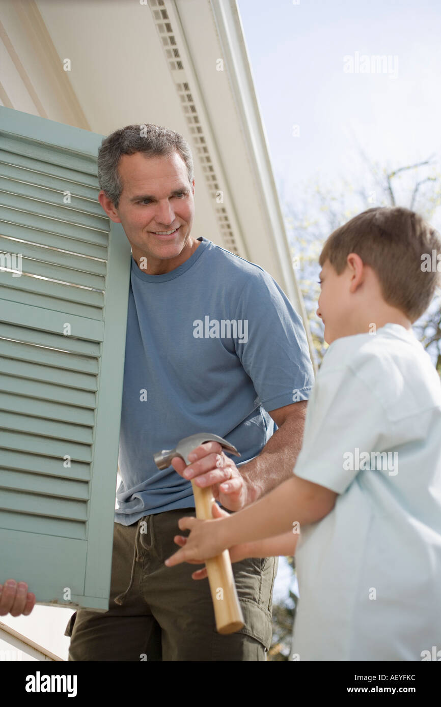 Father and young son fixing shutters Stock Photo - Alamy