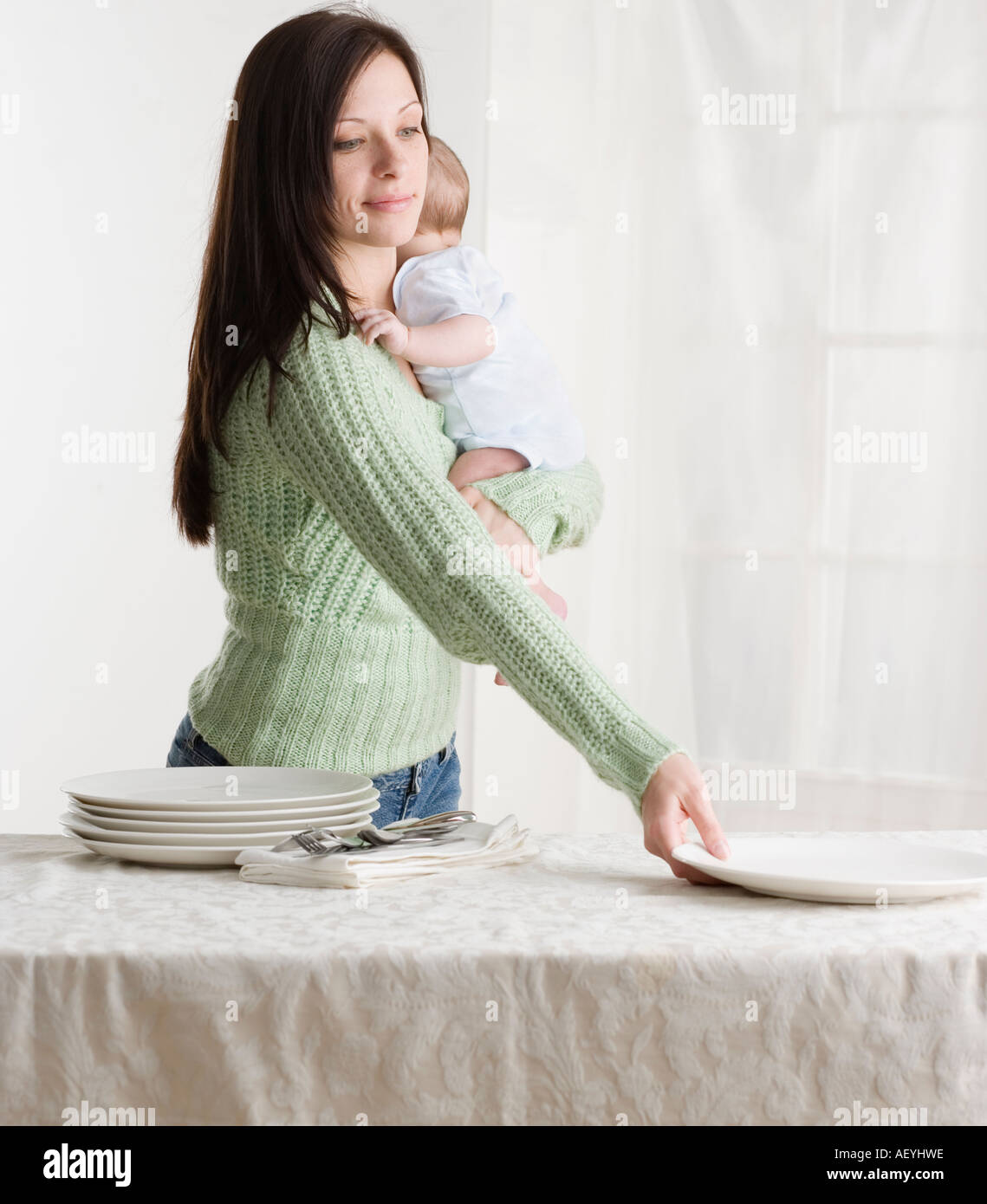 Mother holding baby and setting the table Stock Photo - Alamy