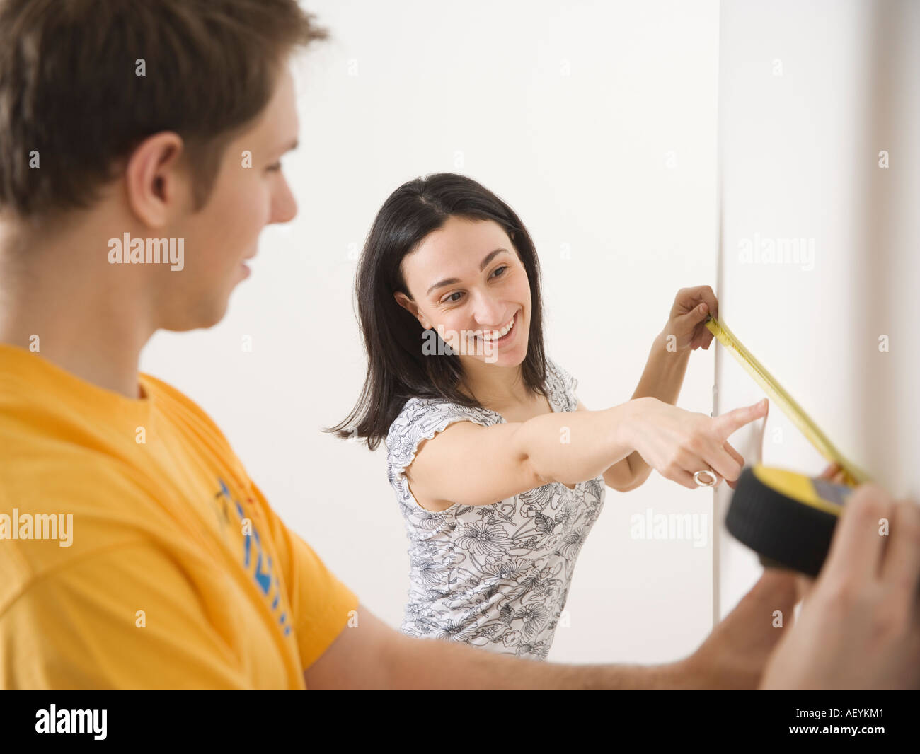 Couple measuring wall Stock Photo - Alamy